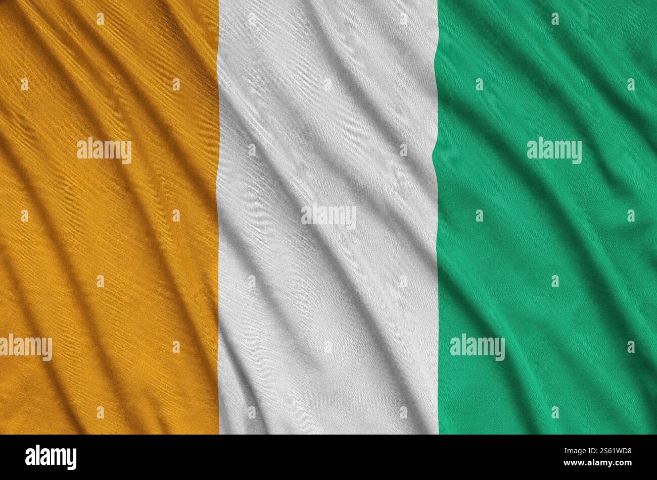 Ivory Coast flag is depicted on a sports cloth fabric with many folds ...
