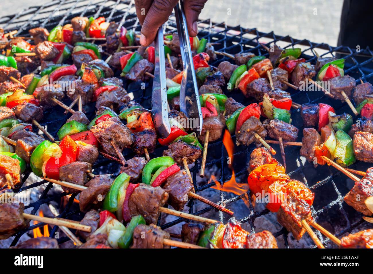 outdoor barbeque , african american man using grill tongs to turn meat ...