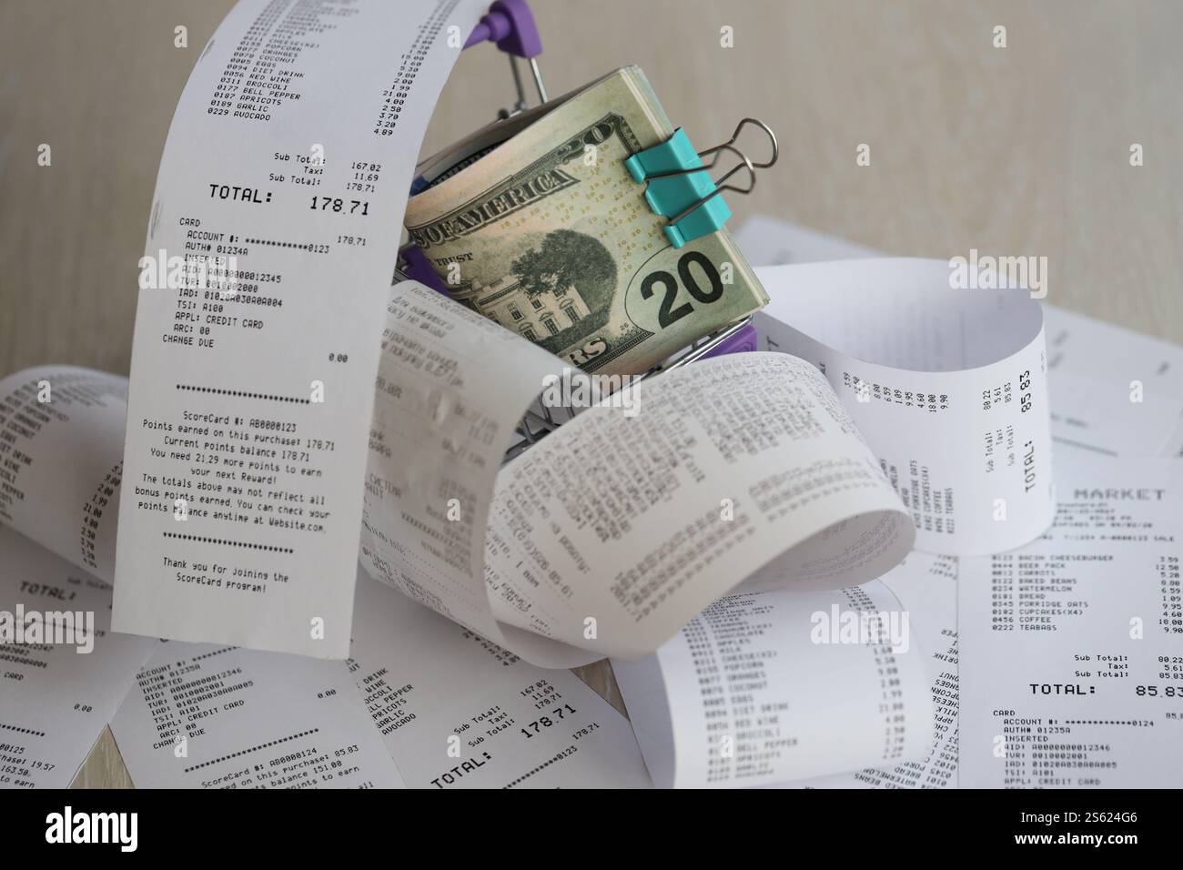 US dollars bunch in shopping trolley surrounded by many paper receipts ...