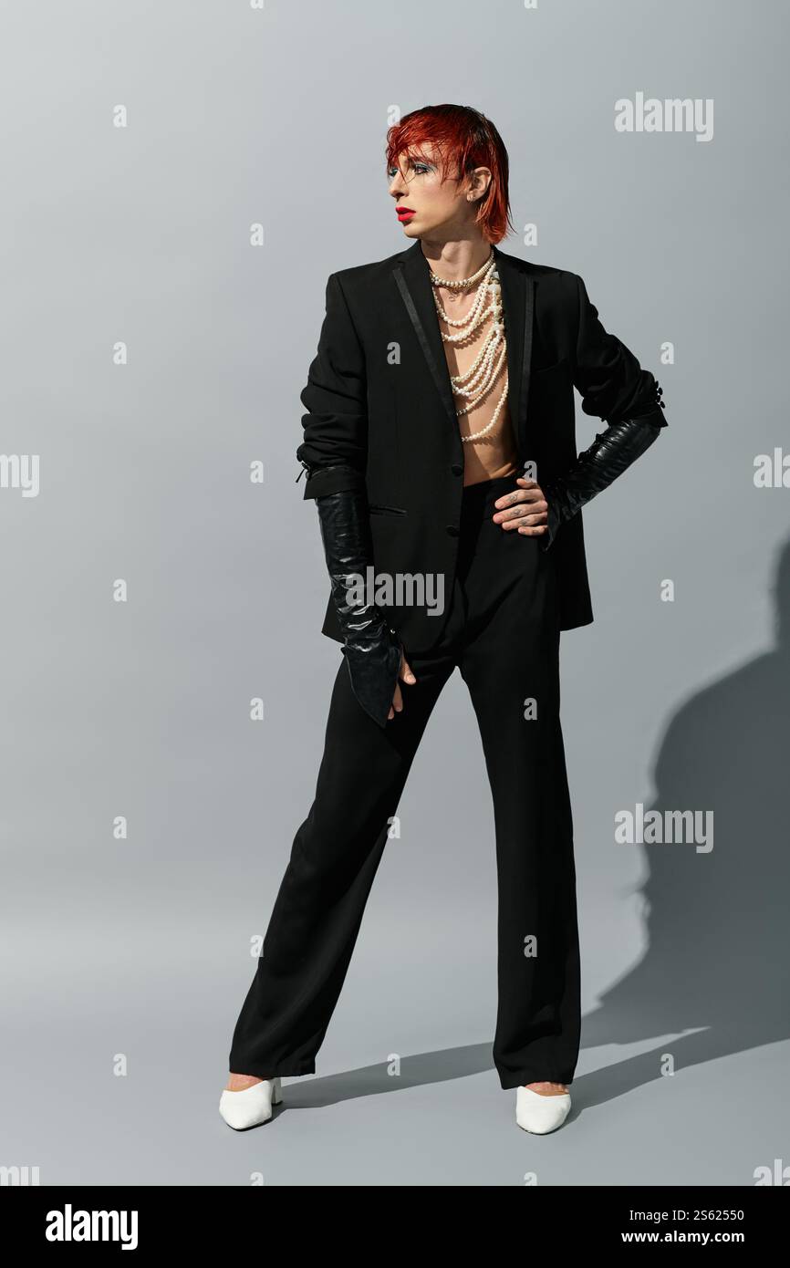 Confident young man in edgy outfit and bold accessories stands against ...