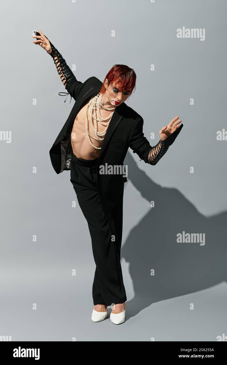 A striking young man in a bold outfit strikes an artistic pose, radiating confidence and flair ...