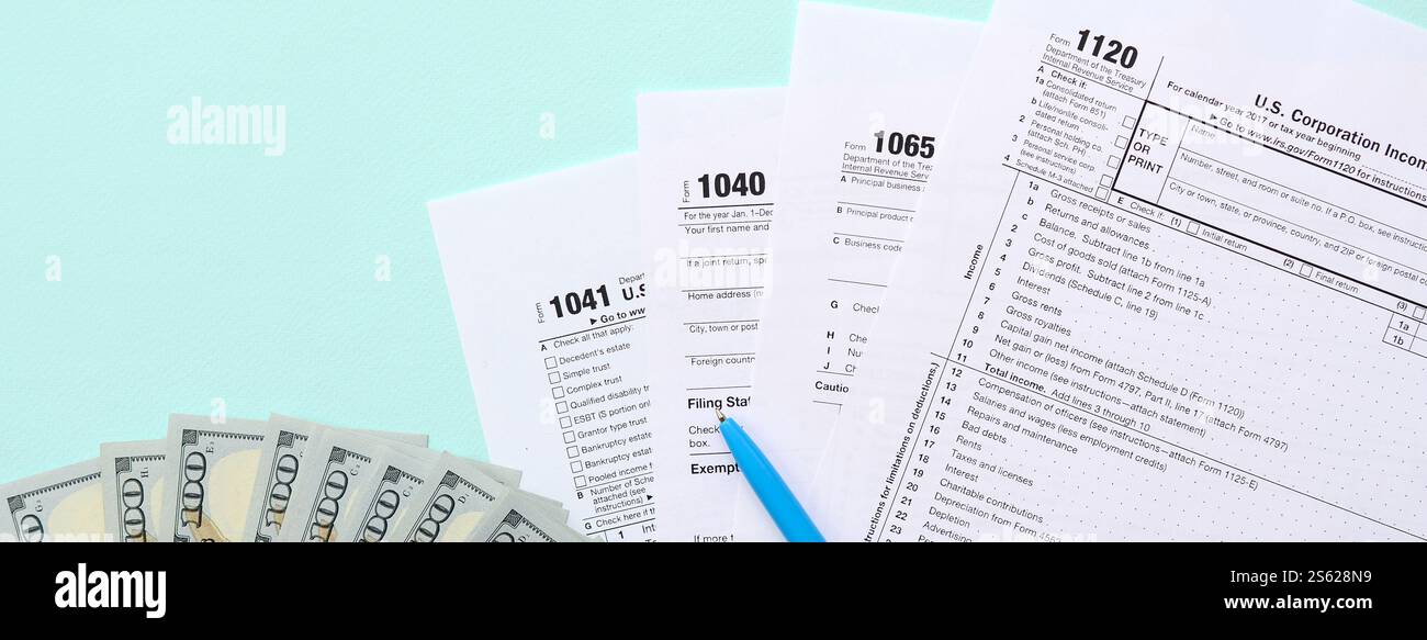 Tax forms lies near hundred dollar bills and blue pen on a light blue ...