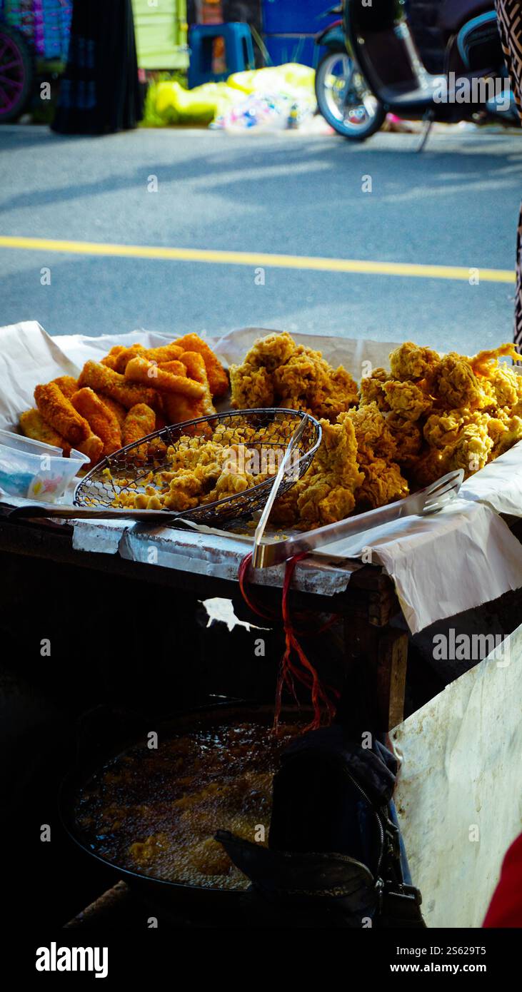 Street food stall with fried snacks including chicken and rolls on a ...