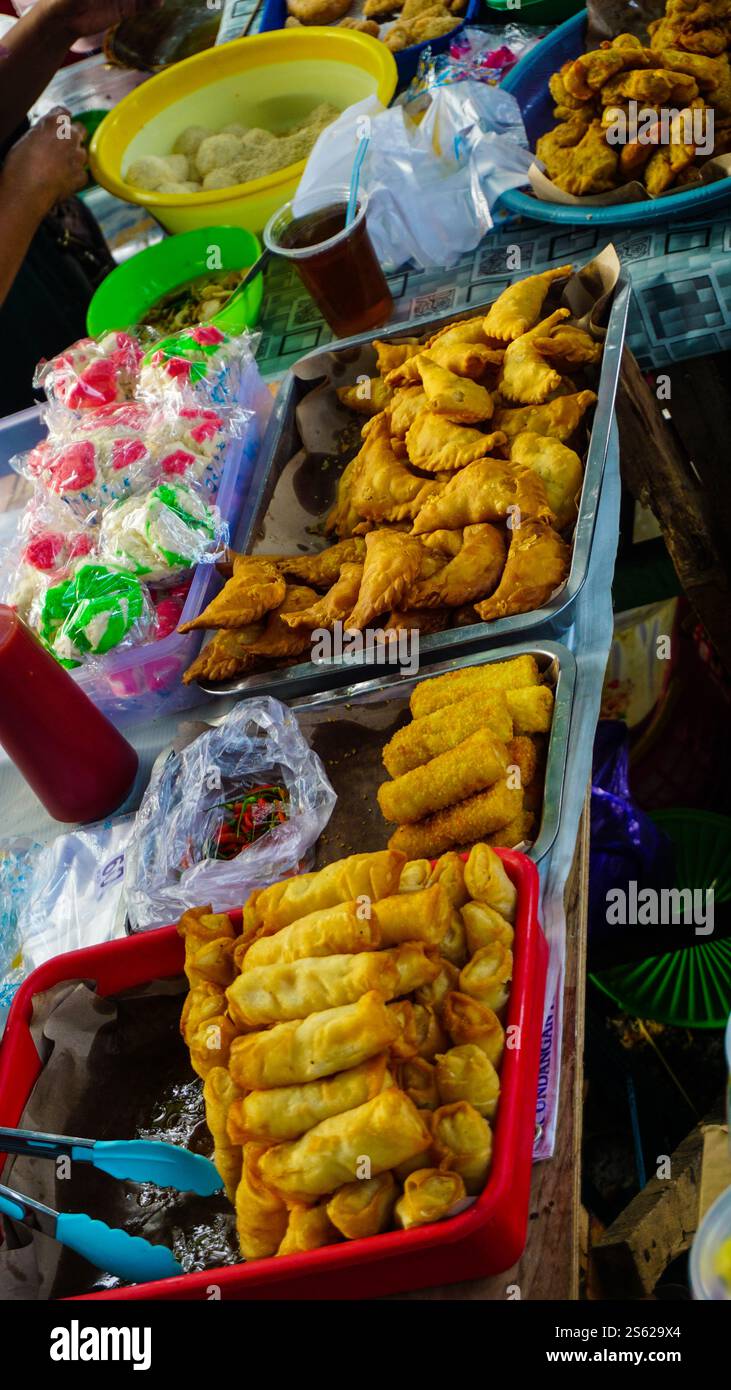A street food stall displaying a variety of fried snacks, including ...
