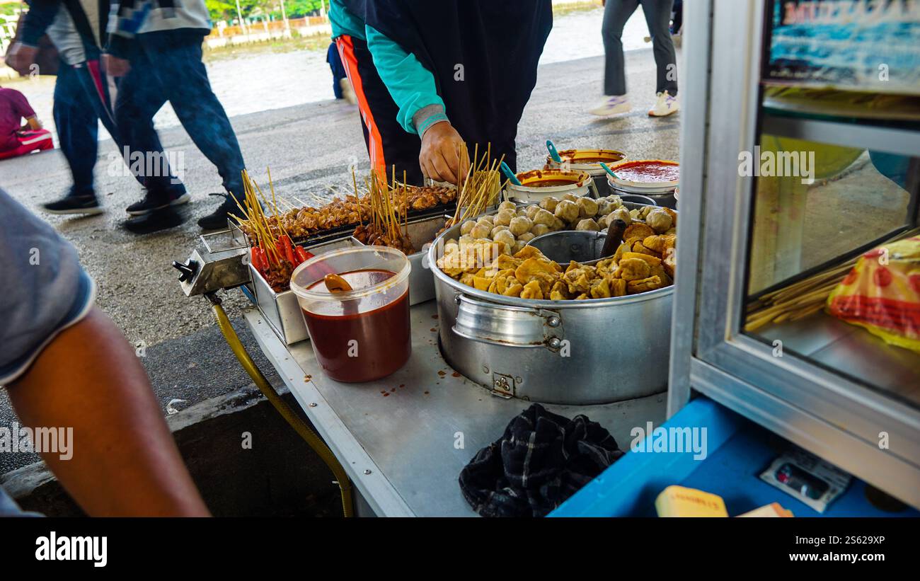 Street food vendor selling skewered meat and fried snacks at an outdoor ...