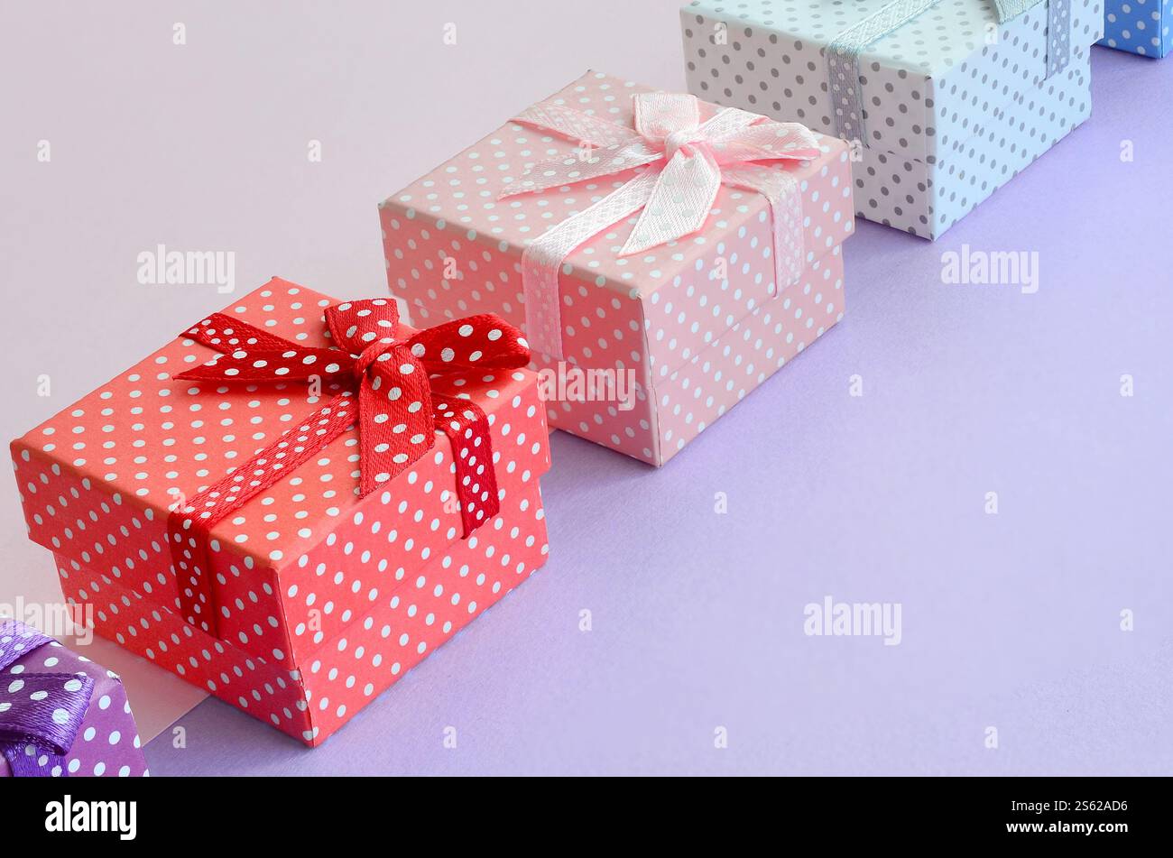 Small gift boxes of different colors with ribbons lies on a violet and ...