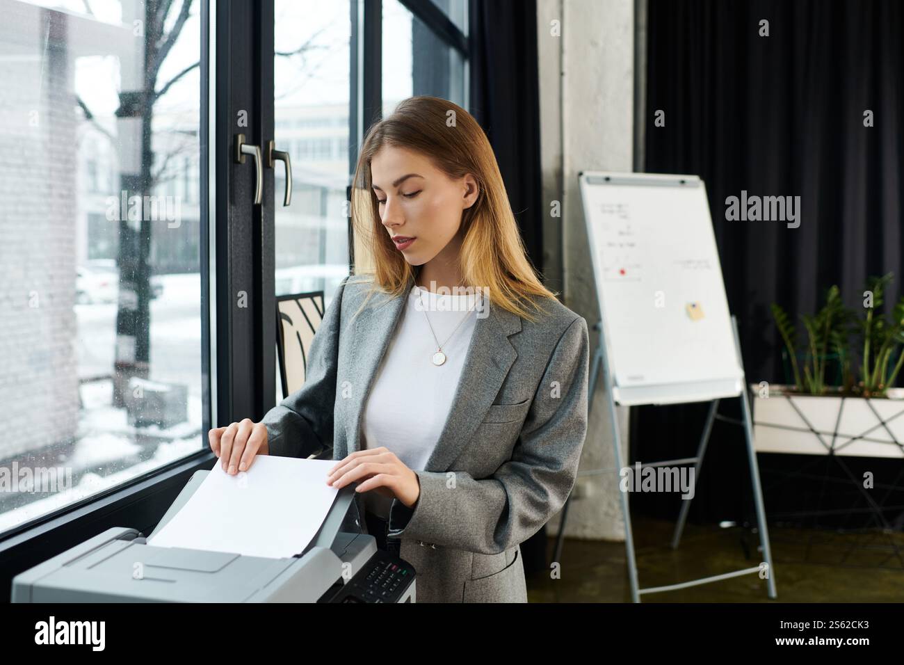 A chic young woman handles printing tasks in a stylish office space ...