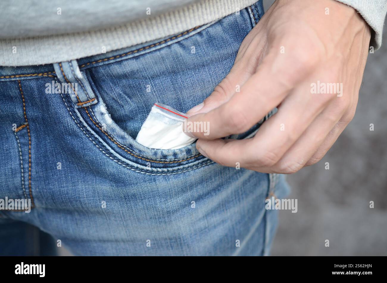 Male hand retrieving drug packet our of blue jean pocket with copy ...