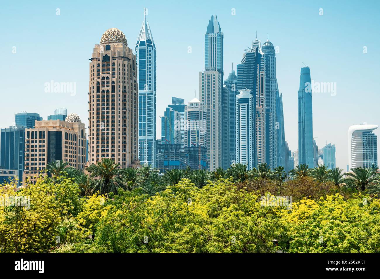 Modern Dubai skyline with tall skyscrapers behind lush greenery and ...