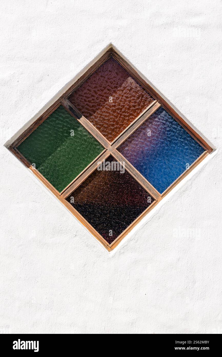 rhombus shape stained glass window is embedded in gray wall rough ...