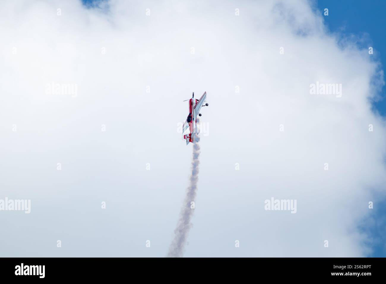 Red plane Sukhoi Su-31 flying high stunts in cloudy sky during an ...