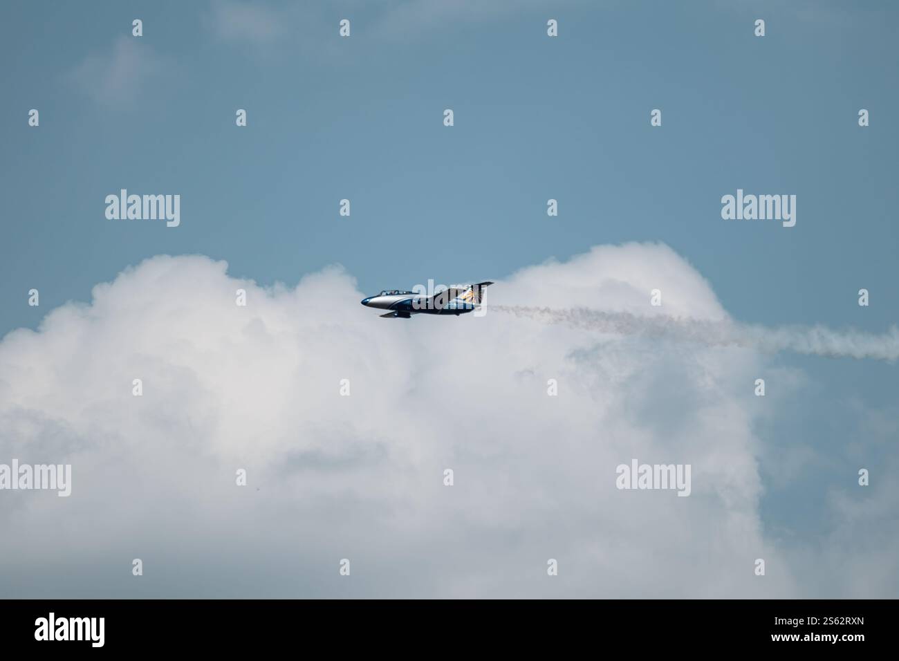 Shiny Aero L-29 Delfín jet plane flying in clouds on sky background ...