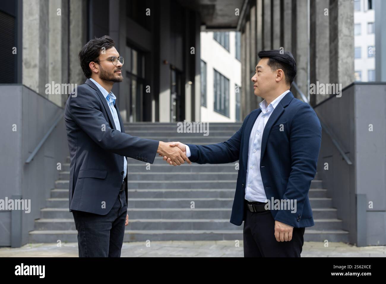 Two serious men in business suits greet each other shaking hands ...