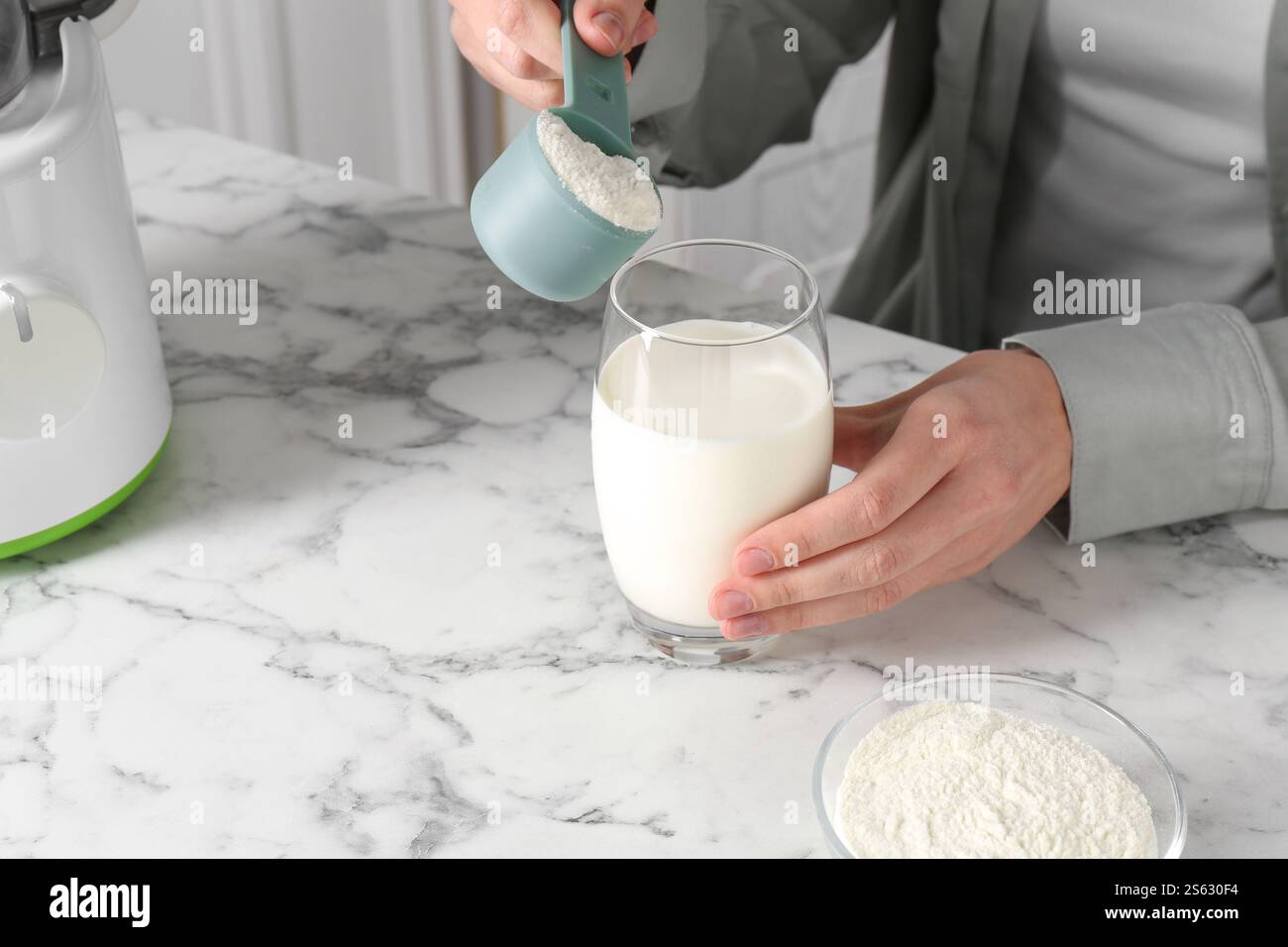 Making protein cocktail. Woman adding powder into glass with milk at ...