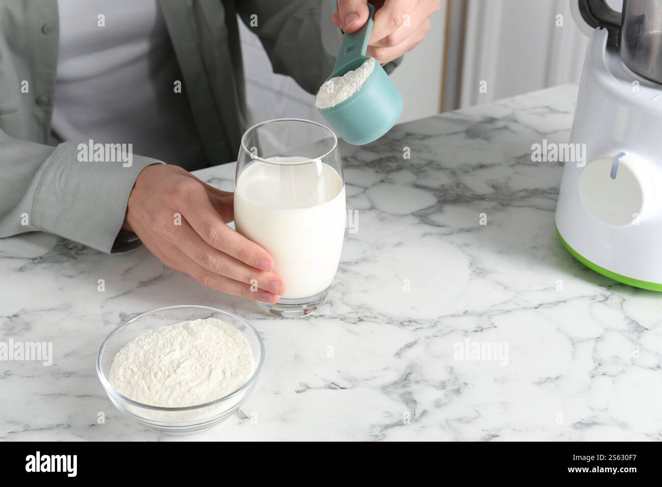 Making protein cocktail. Woman adding powder into glass with milk at ...