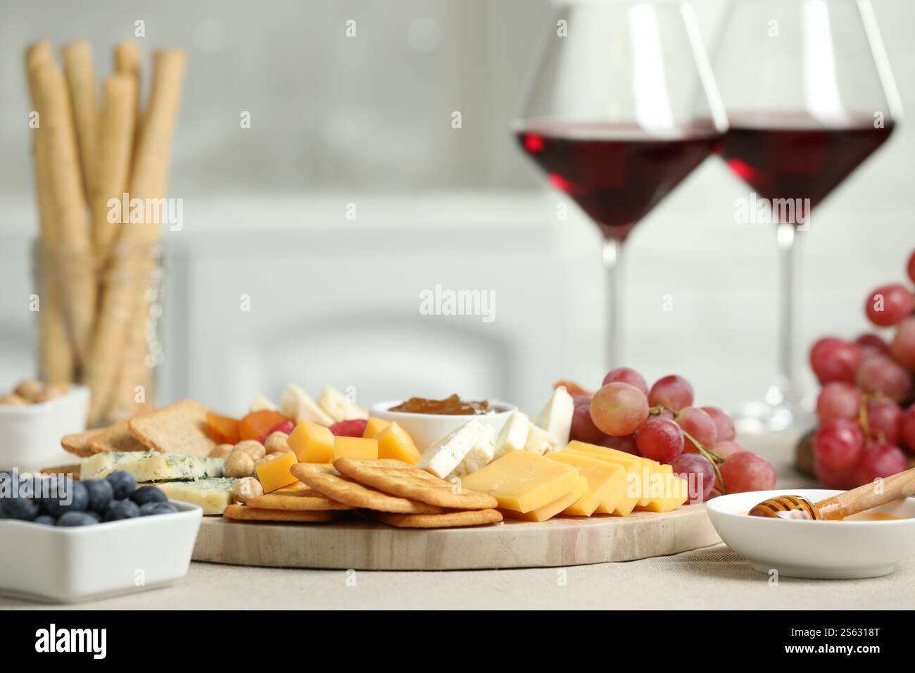 Different types of cut cheese and other snacks on light textured table ...