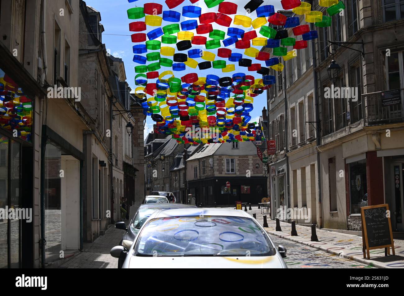 Light passes through coloured rings suspended above a street in Laon ...