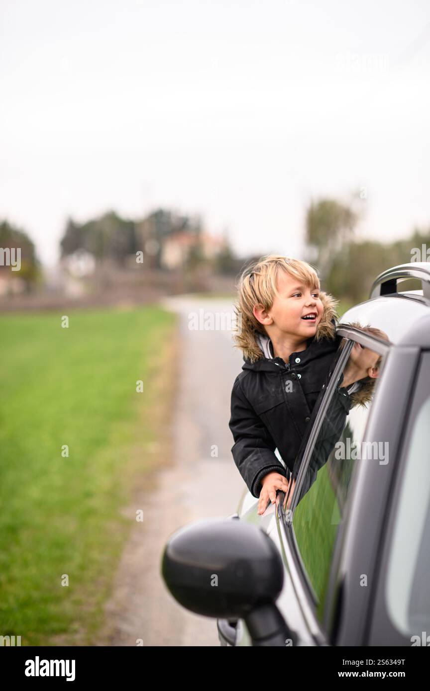 Boys lean out of a moving car’s windows, laughing and enjoying the ...