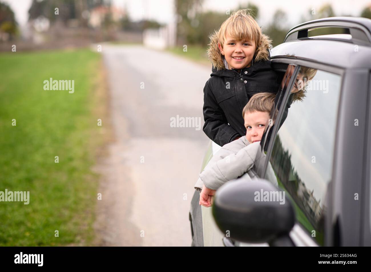 Boys lean out of a moving car’s windows, laughing and enjoying the ...