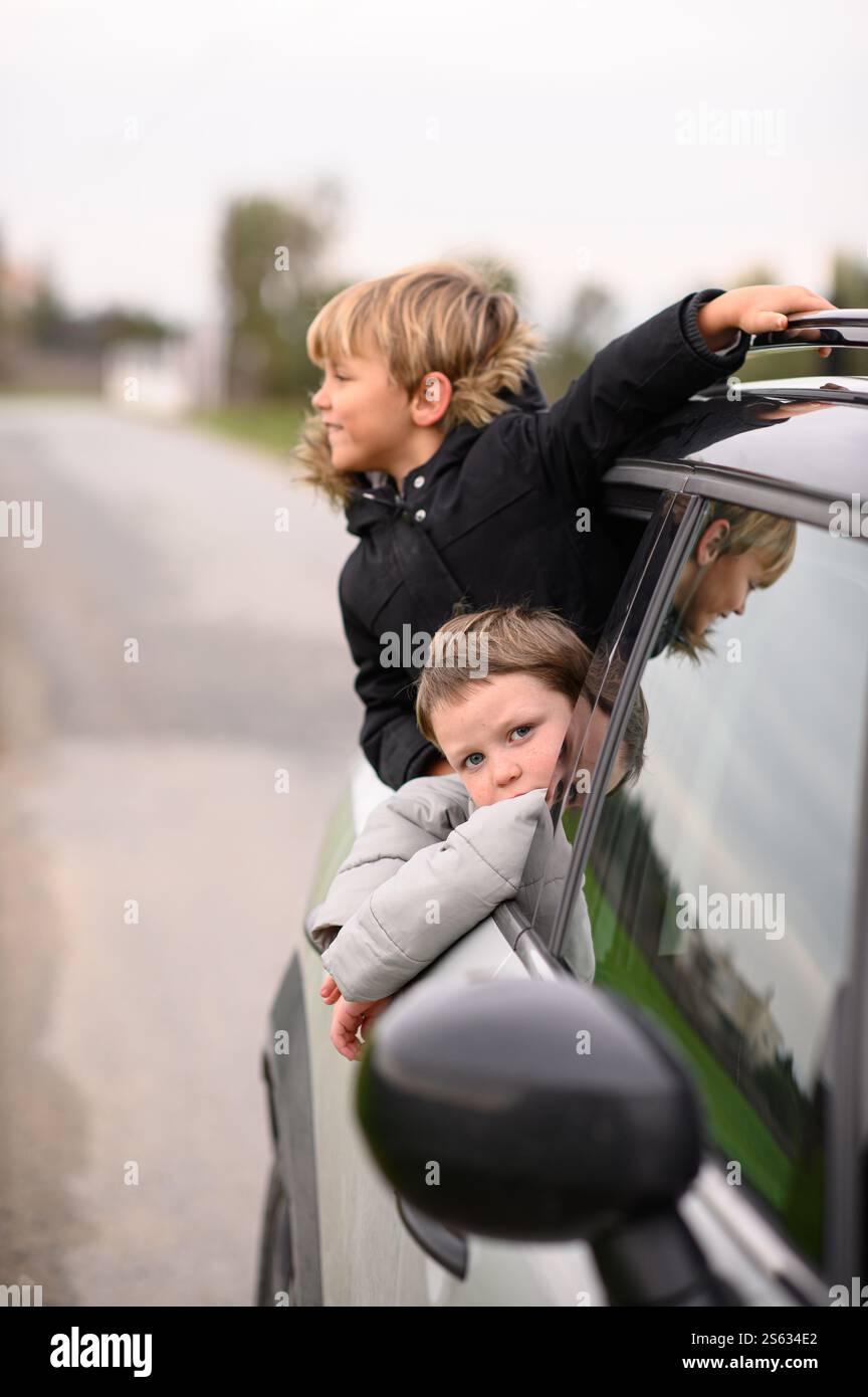 Boys lean out of a moving car’s windows, laughing and enjoying the ...