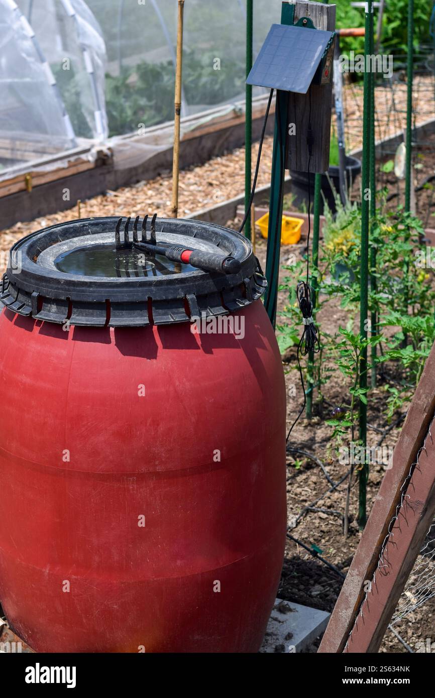 Rain barrel in a community garden with a small solar panel Stock Photo ...