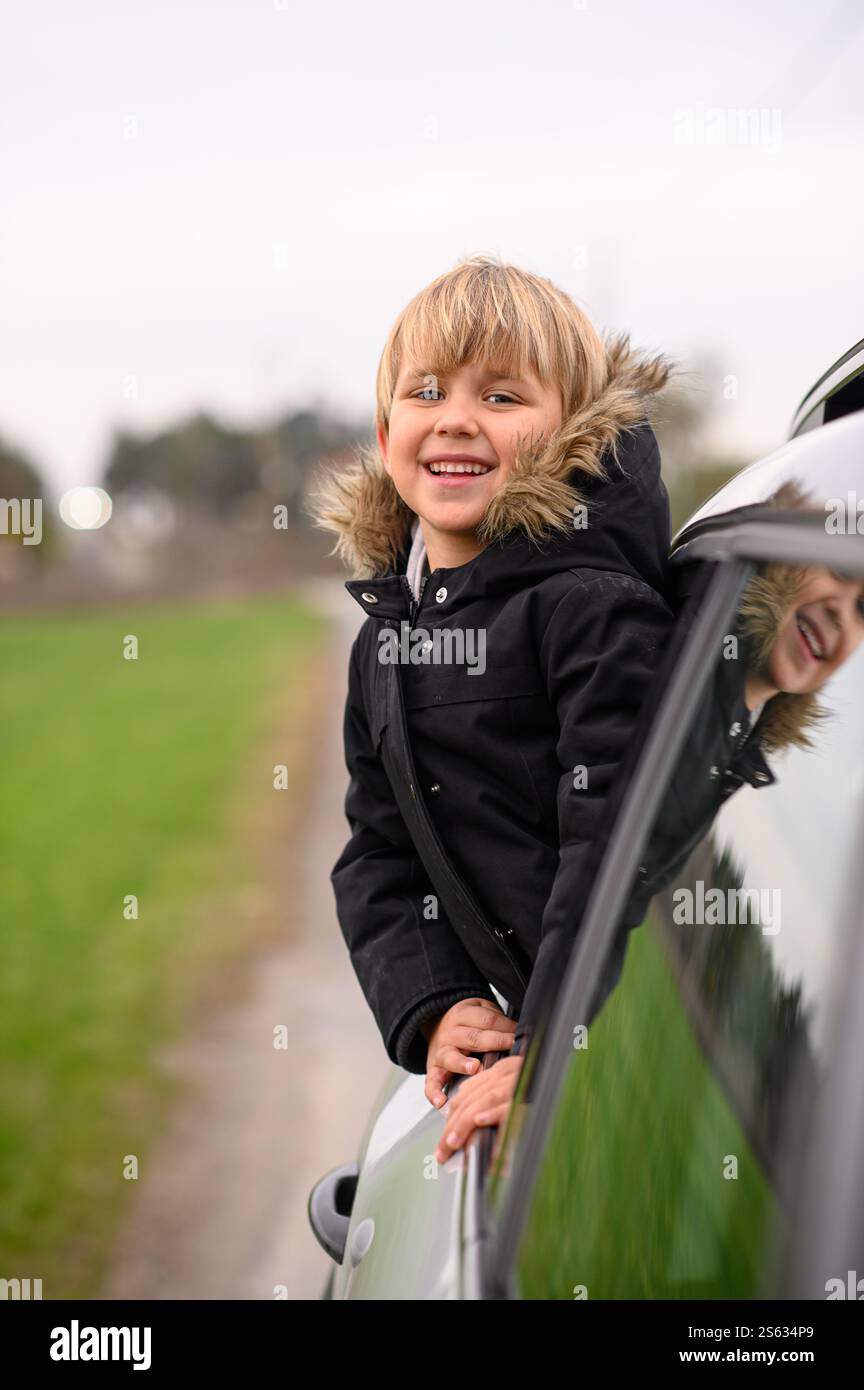Boys lean out of a moving car’s windows, laughing and enjoying the ...
