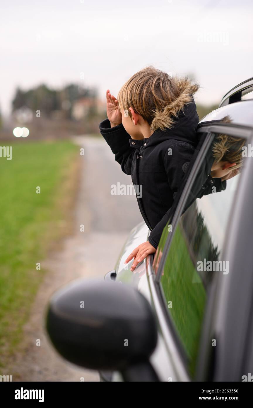 Boys lean out of a moving car’s windows, laughing and enjoying the ...