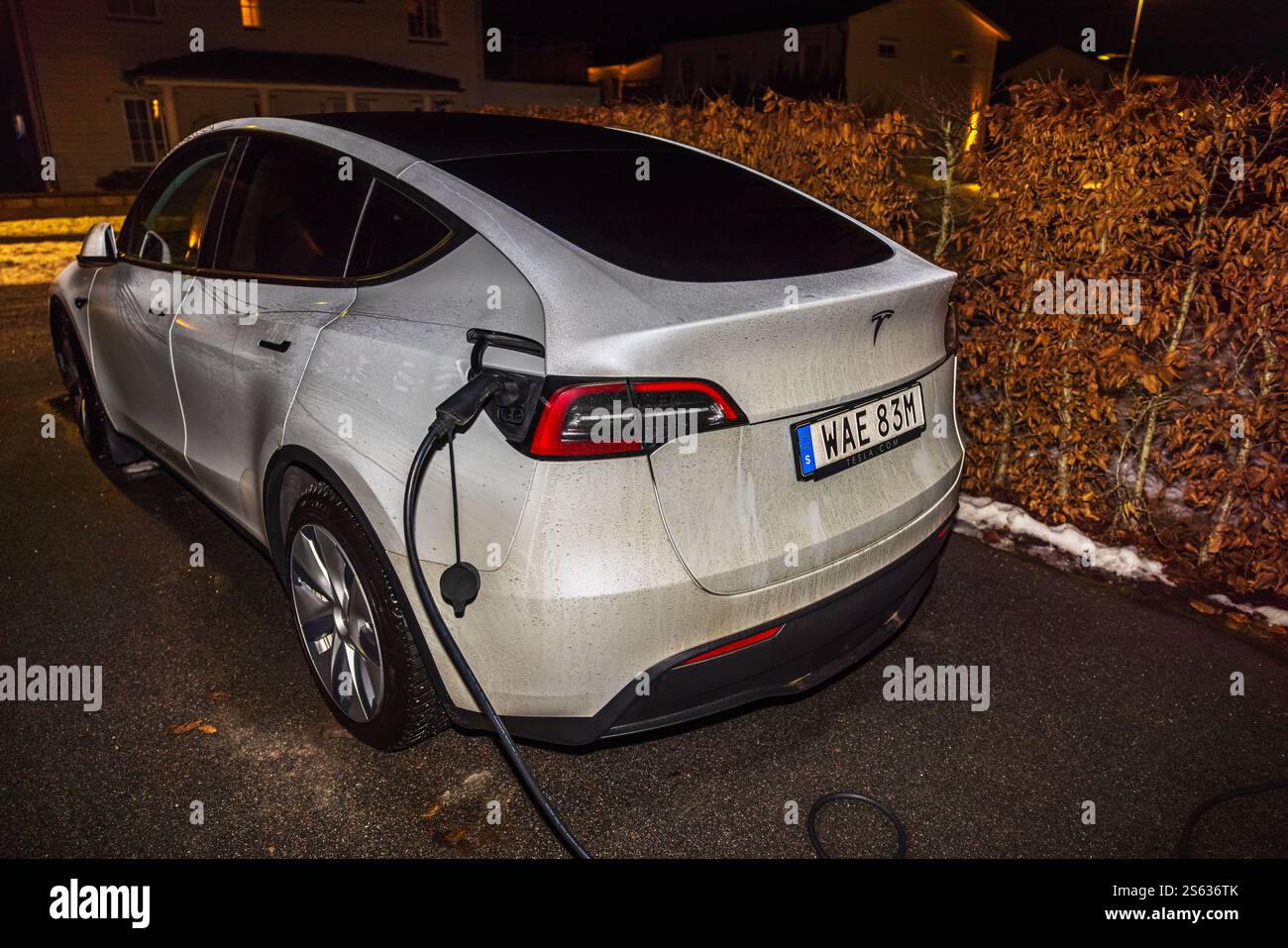 Tesla Model Y electric SUV charging in residential area at night with ...