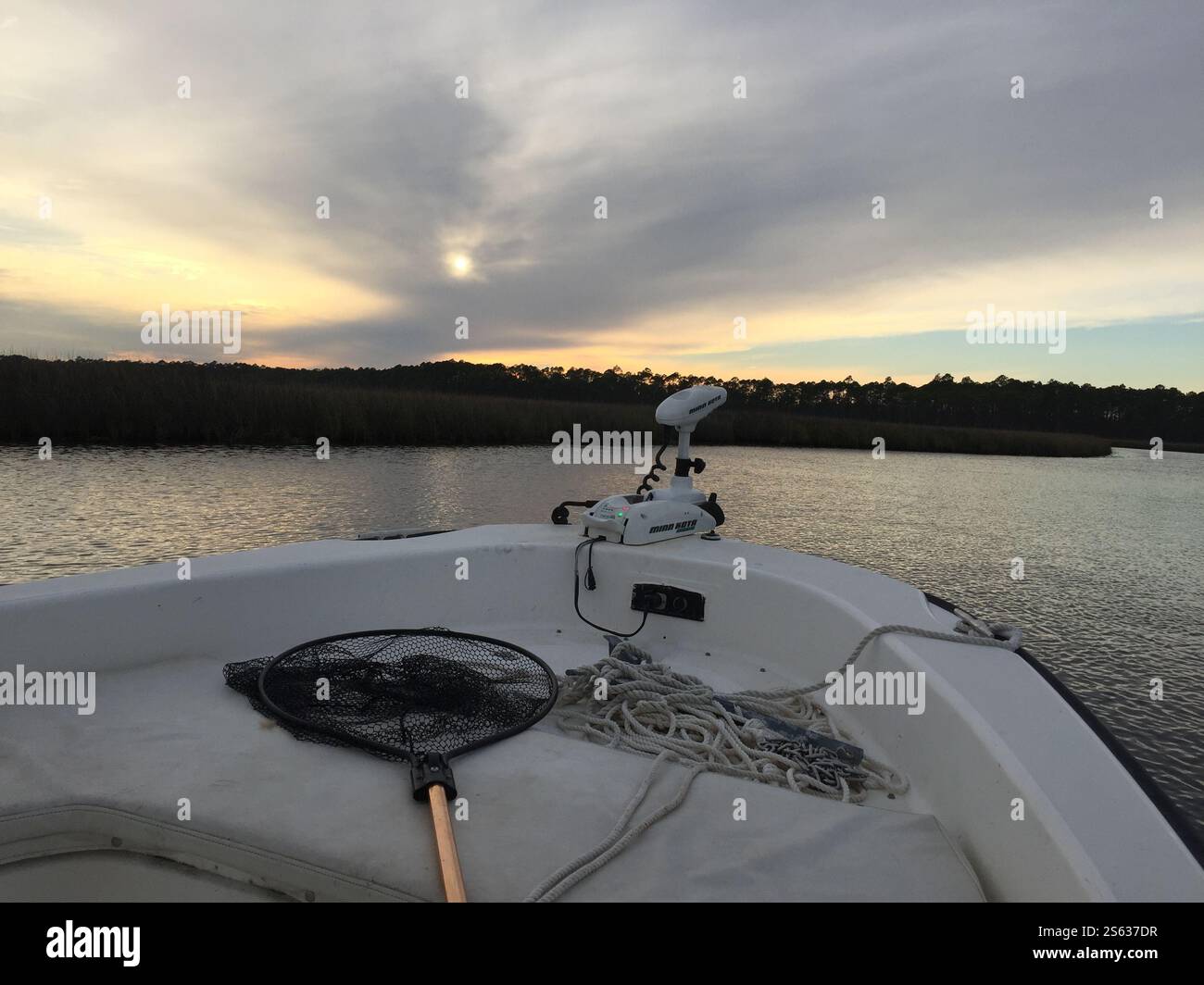 The image shows the front deck of a small boat on a calm waterway ...