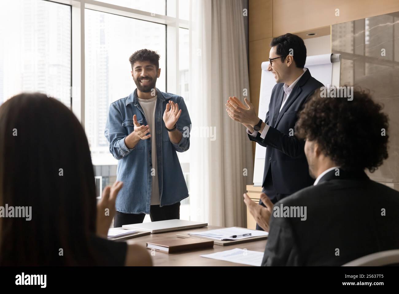 Team clapping hands welcoming new company member in boardroom Stock ...