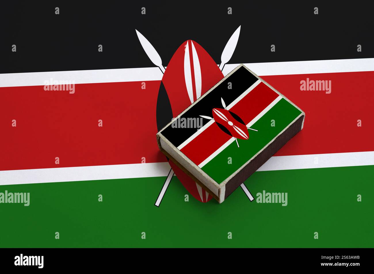 Kenya flag is pictured on a matchbox that lies on a large flag. Kenya ...
