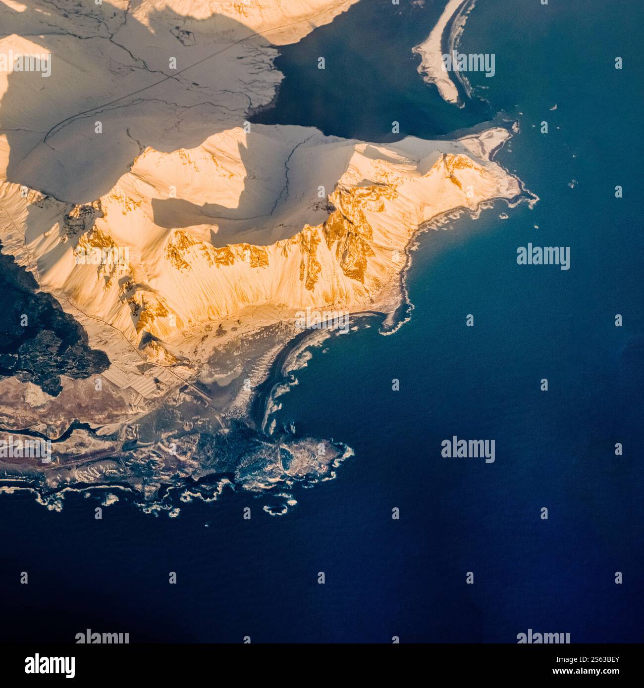 Aerial view of golden-lit snowy coastline in Hornafjordur, south ...