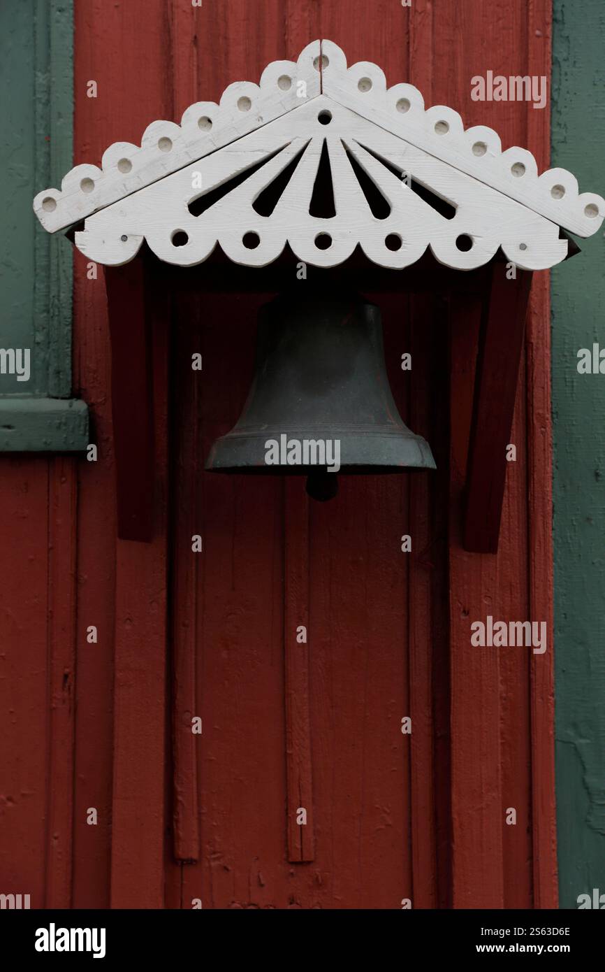 A closed up view of a church bell with red and white painted wooden ...