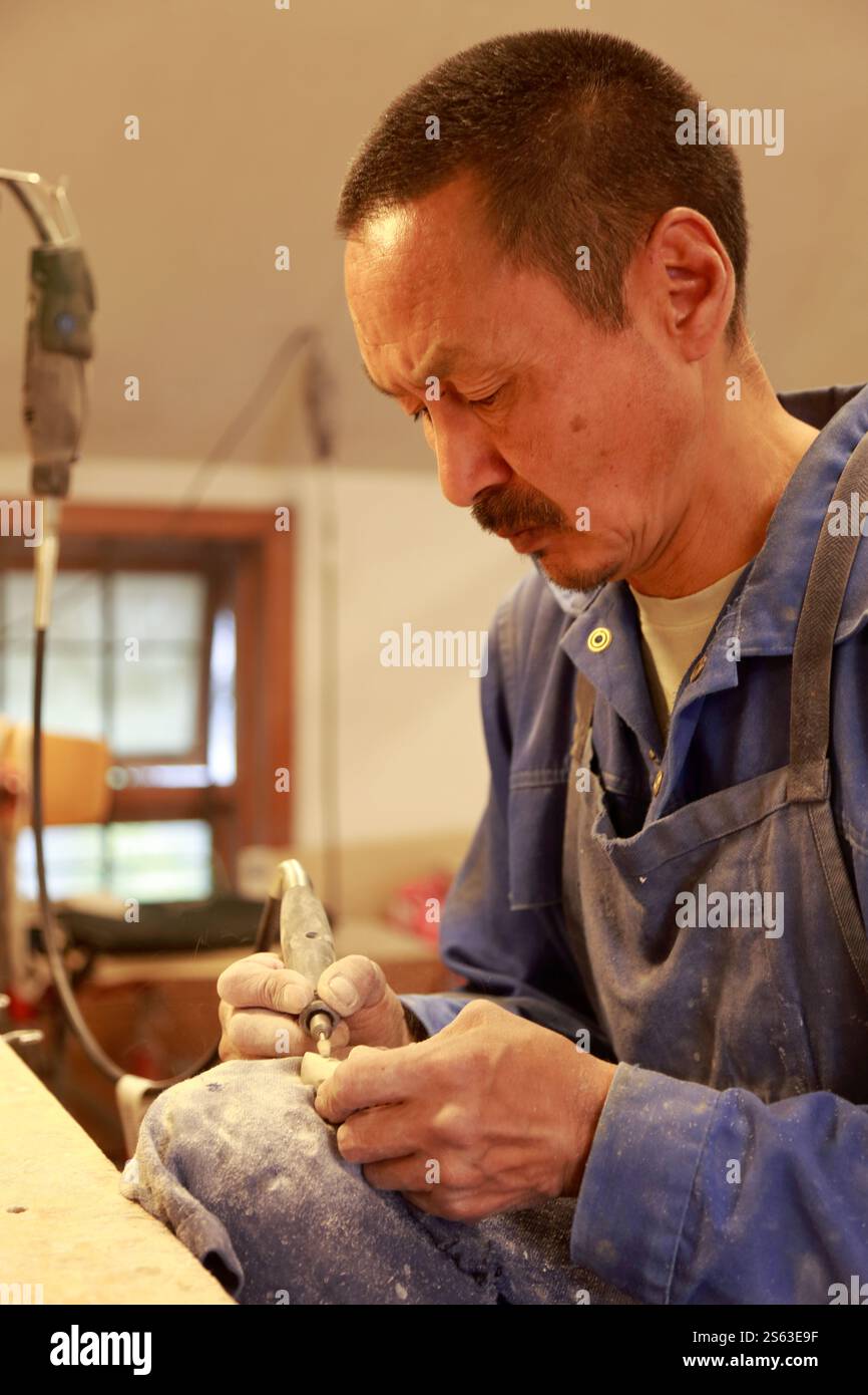 An Inuit craftsman making a whale bone carving in a handcraft workshop ...