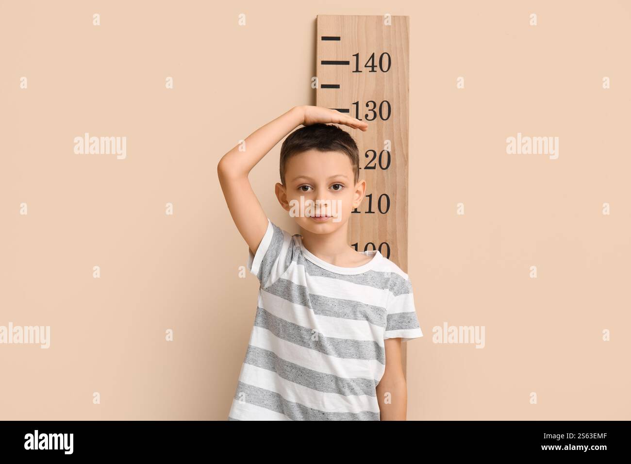 Cute little boy measuring height on beige background Stock Photo - Alamy