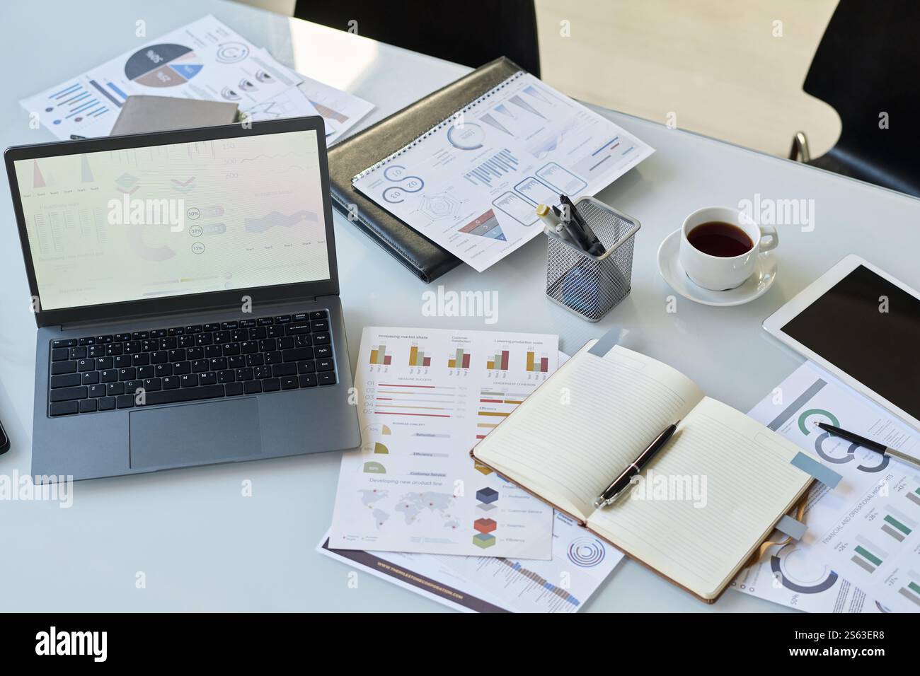 Laptop with charts and diagram on screen standing among papers ...