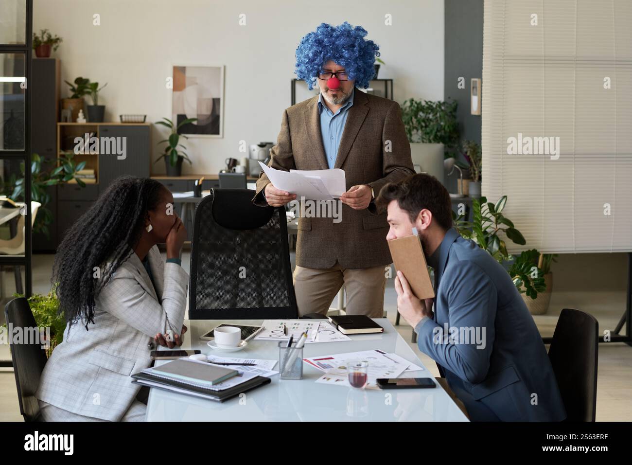 Two young intercultural employees laughing and making fun of their boss ...