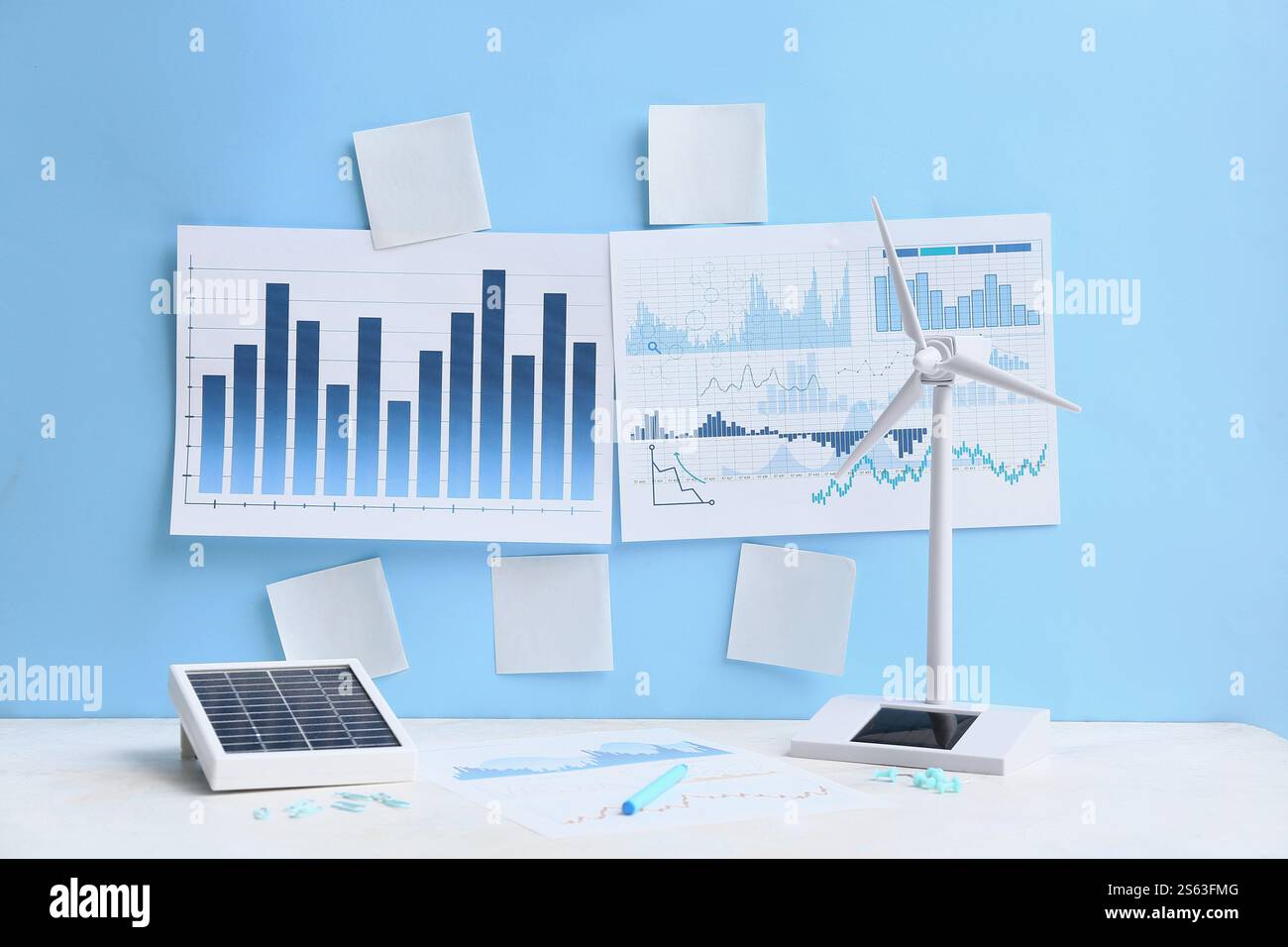 Diagrams with blank sticky notes and wind turbine model on table near ...