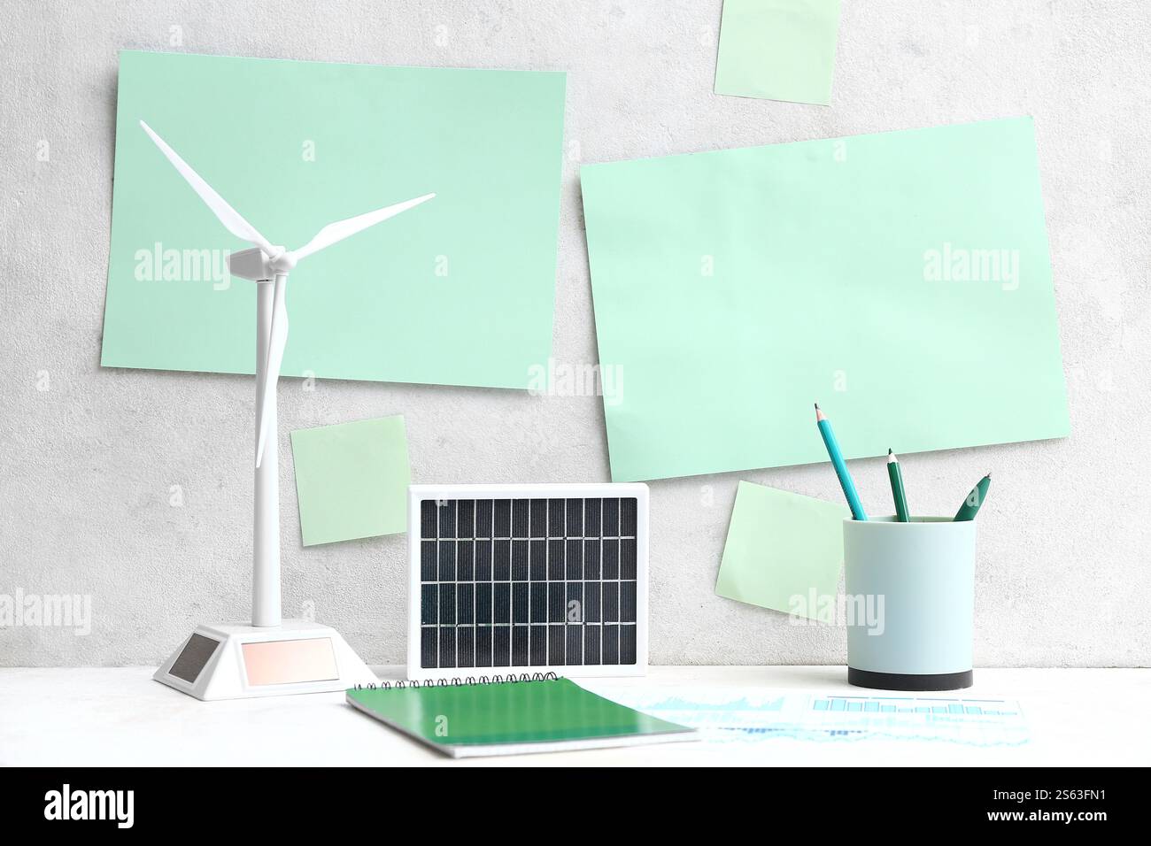 Blank papers with wind turbine model and solar panel on table near ...