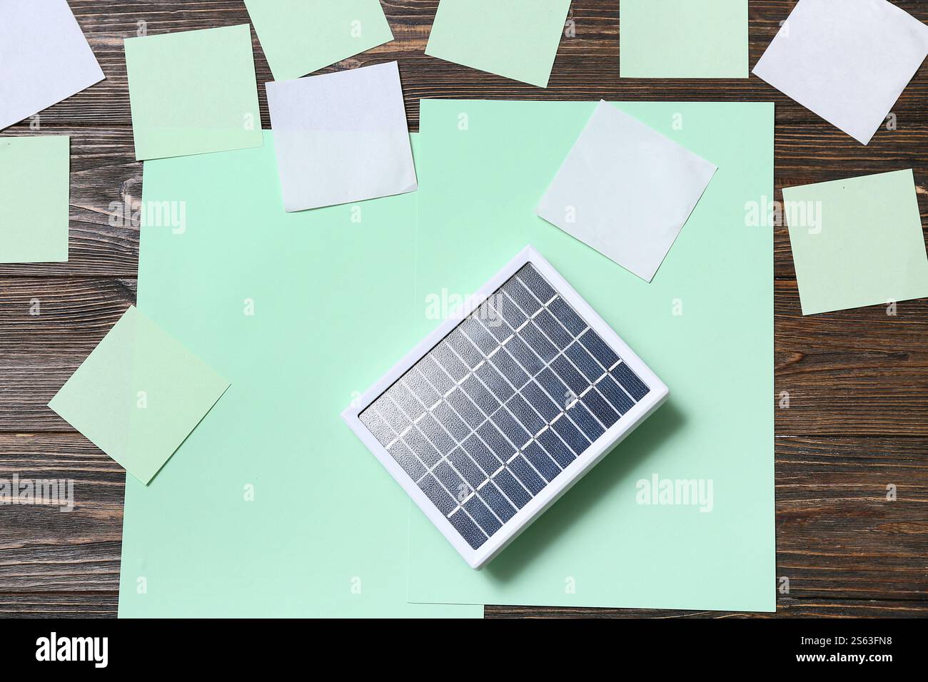 Blank papers with portable solar panel on wooden background. Green ...