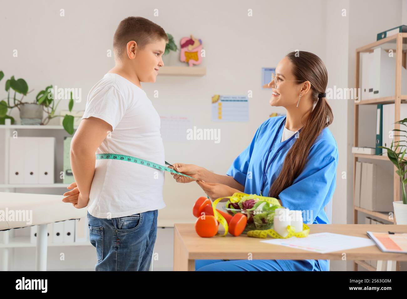 Female nutritionist measuring overweight boy's belly in clinic. Diet ...