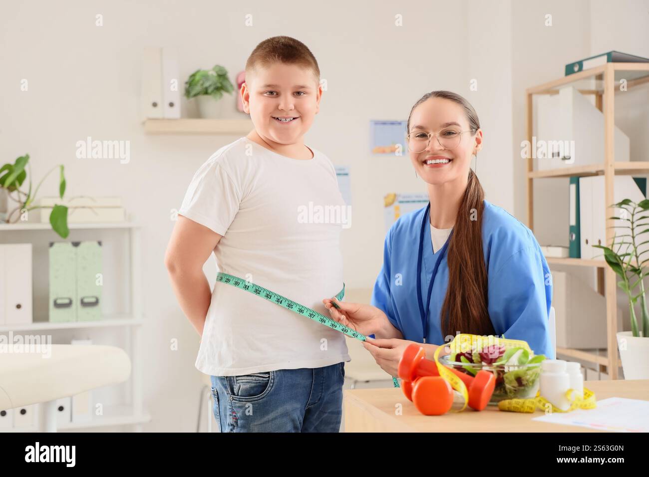 Female nutritionist measuring overweight boy's belly in clinic. Diet ...