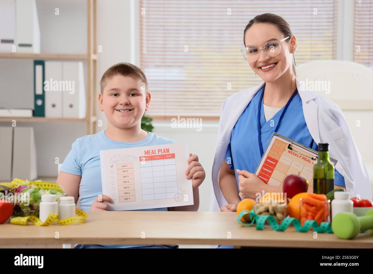 Overweight boy with meal plan and nutritionist at table in clinic. Diet ...