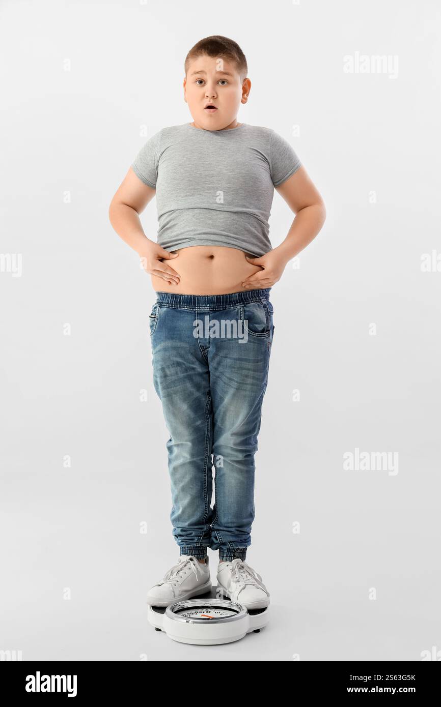 Shocked overweight boy measuring weight on light background. Diet ...