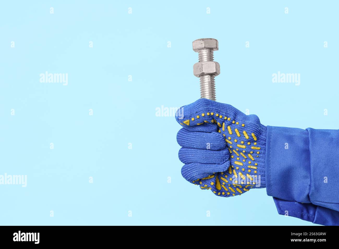Mechanic's hand holding bolt with nut on blue background Stock Photo ...