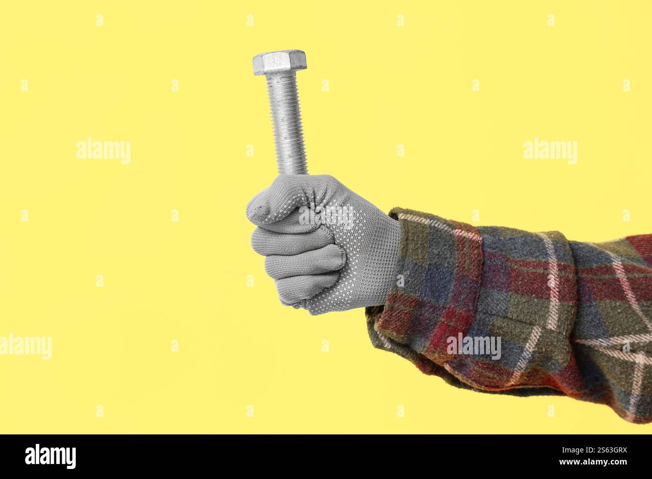 Mechanic's hand holding bolt on yellow background Stock Photo - Alamy