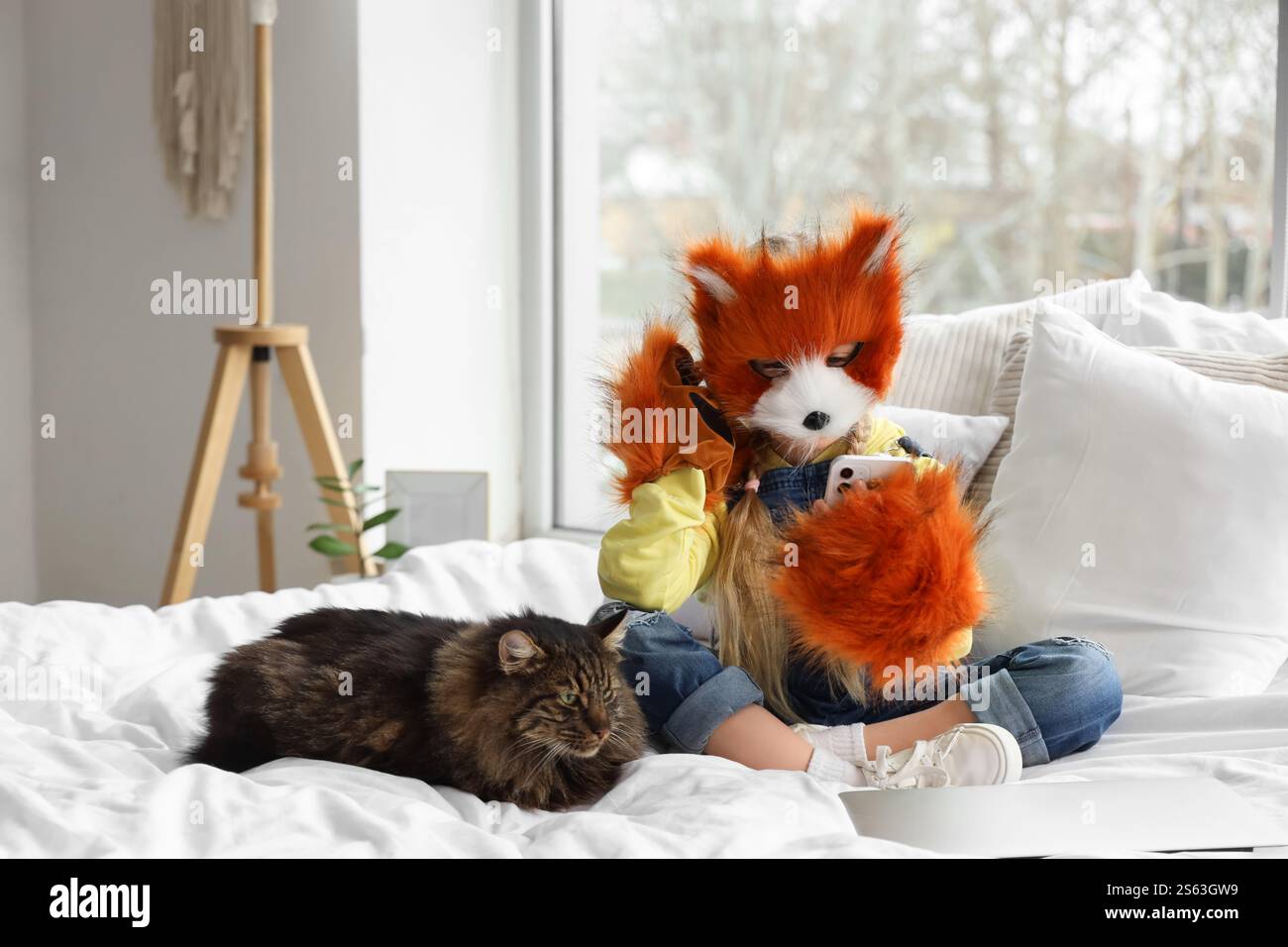 Quadrober girl dressed as fox with mobile phone and cute cat in bedroom ...