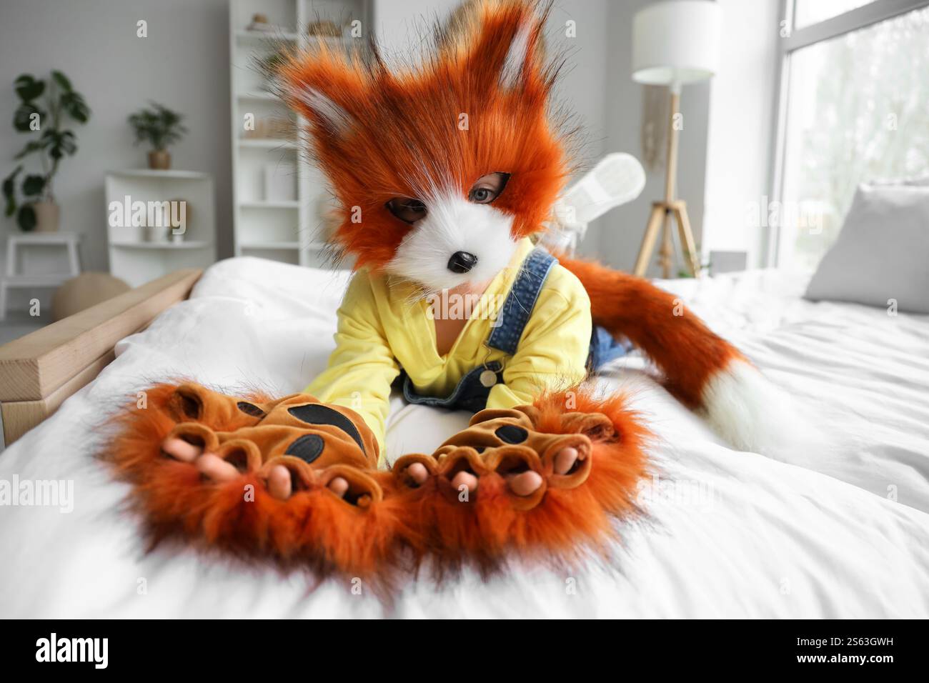 Quadrober girl dressed as fox lying in bedroom Stock Photo - Alamy