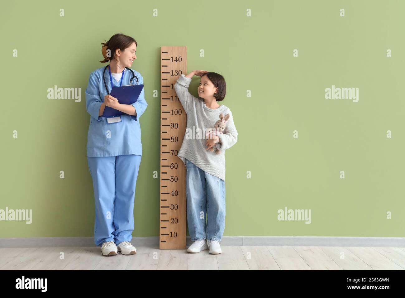 Female pediatrician and Asian girl measuring height with stadiometer ...