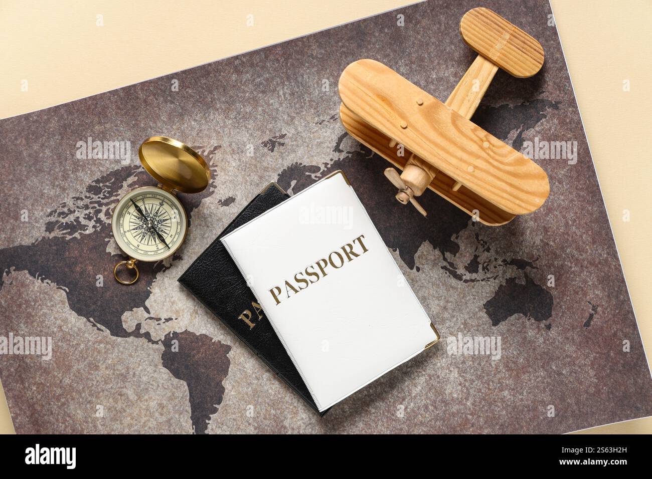Passports, wooden plane, compass and world map on color background ...